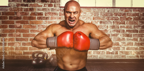 Angry bald boxer with punching gloves against gym - Buy this stock ...