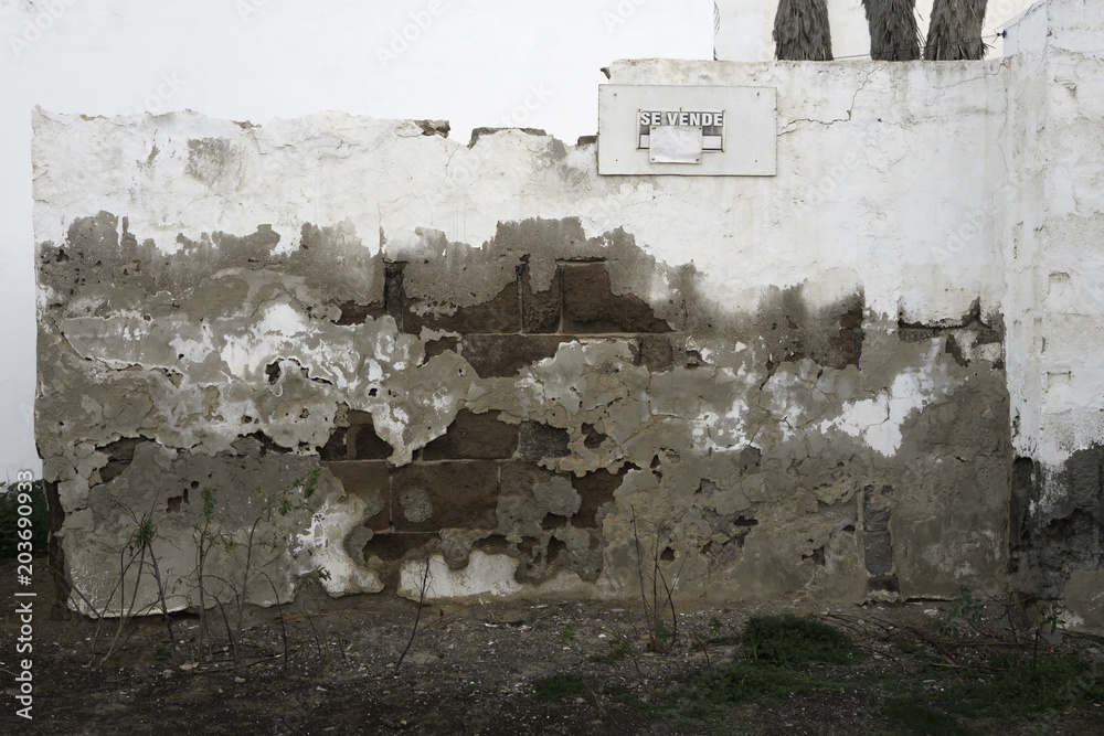 Dilapidated wall of building with a For Sale sign (Se Vende), plaster ...