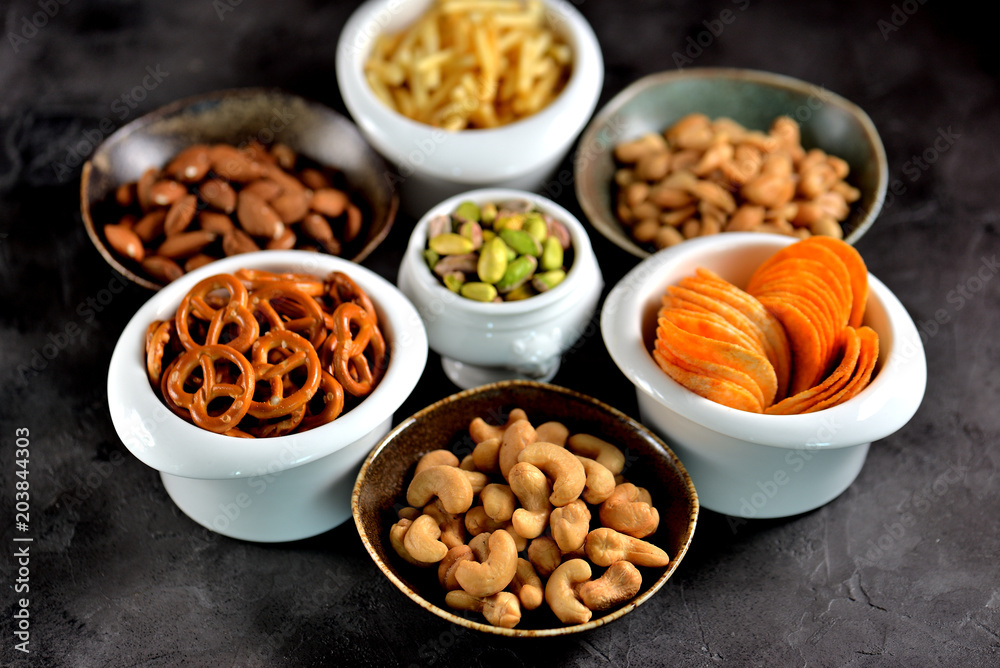 Different kinds of snacks - chips, salted peanuts, cashews, almonds and ...