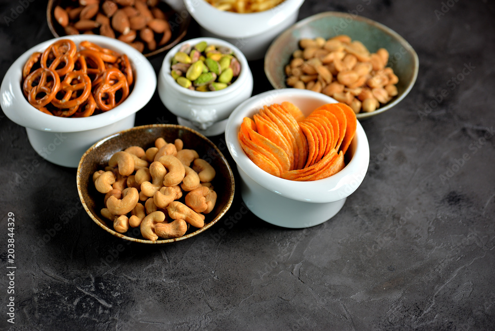 Different kinds of snacks - chips, salted peanuts, cashews, almonds and ...