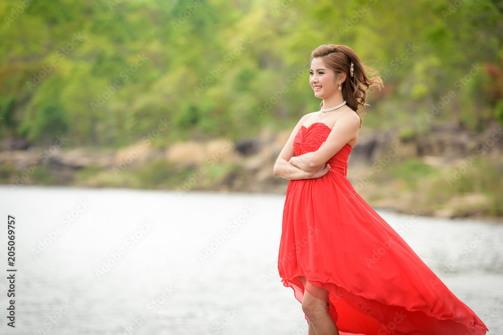 Beautiful woman wear red evening dress over mountains and rivers ...