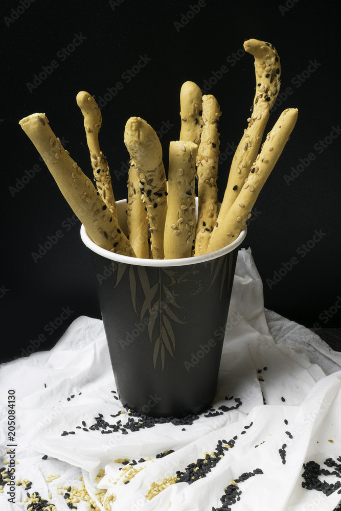 homemade snack, baked sticks with sesame and black cumin in the paper ...