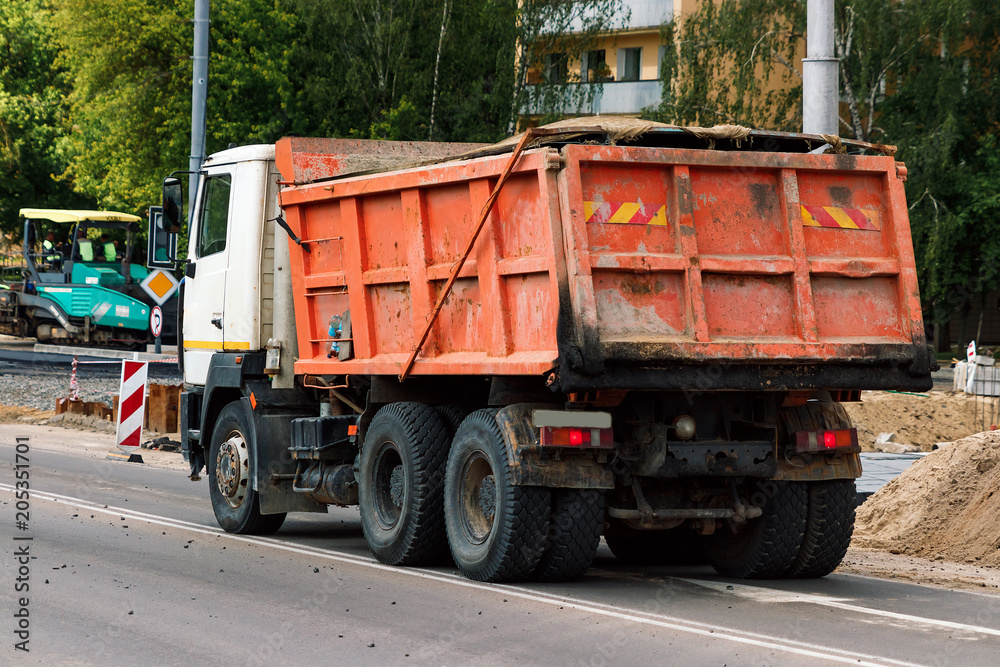 Powerful big rig compact semi truck tipper moves on the road through an ...