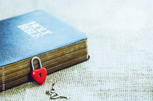 The compass lean on holy bible with Red heart key lock on wooden table ...