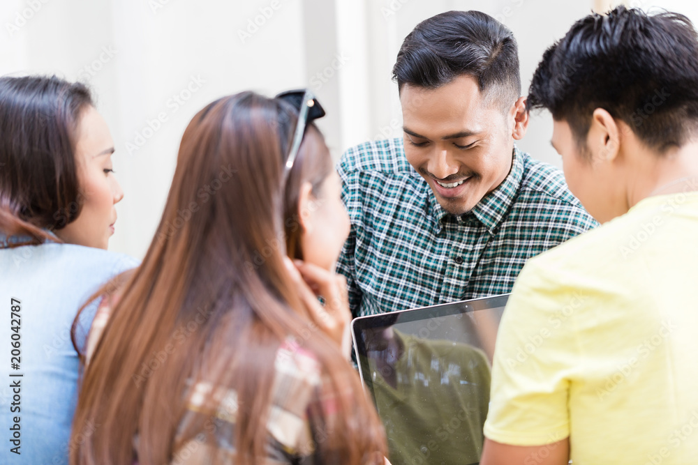 Four young employees sharing opinions and information while interacting ...