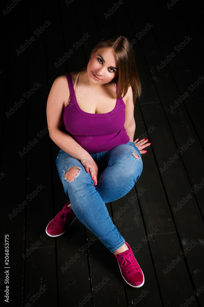 Plus size fashion model in jeans and top, fat woman on black studio ...