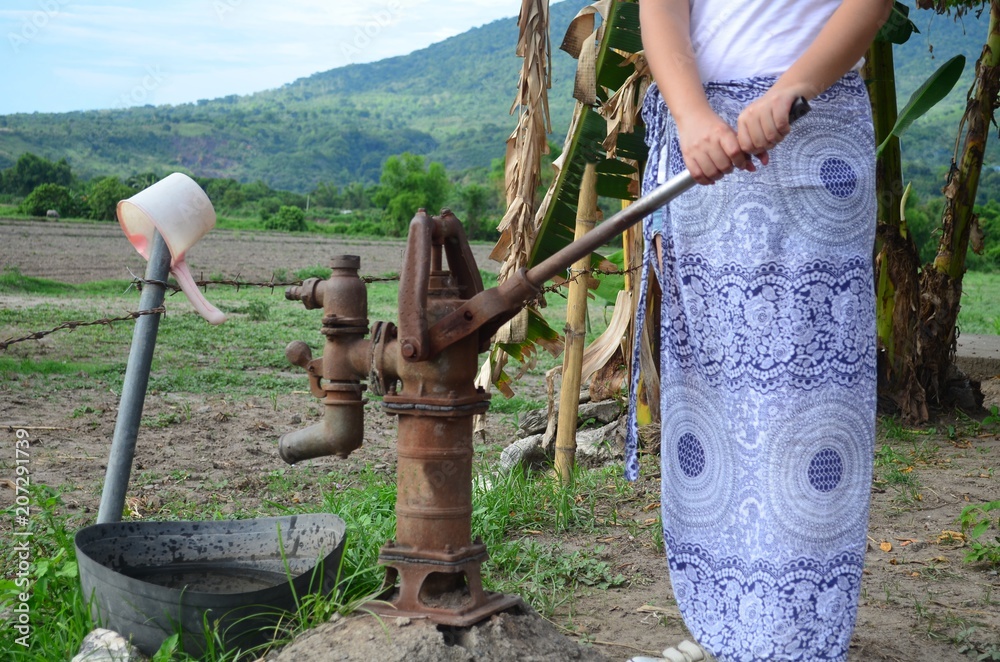 Foto de Stock Beautiful Asian woman on a manual water pump in a small ...