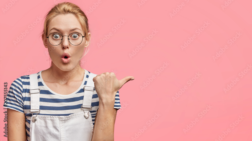 Amazed attractive blonde female with bugged eyes, looks surprisingly at ...