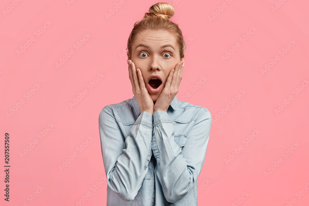 Puzzled astonished female keeps mouth wide opened, stares with ...