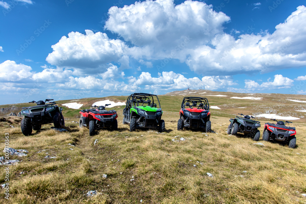 Parked ATV and UTV, buggies on mountain peak with clouds and blue sky ...