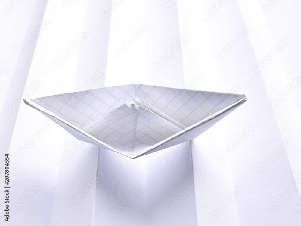 Origami paper white boat floating on a folded sheet of paper, like ...