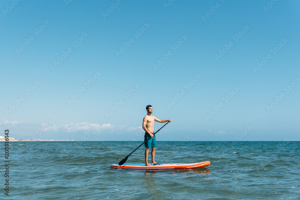 Shirtless man on paddleboard Stock Photo | Adobe Stock