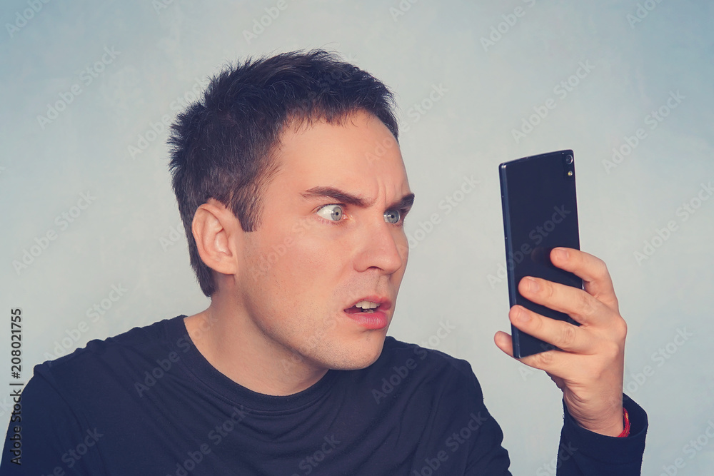 Photo Stock Disgusted man reading a text message. guy looks at the ...