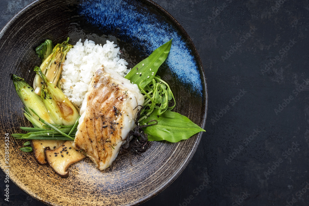 Modern Japanese fried cod fish filet with bok choi and rice as top view ...