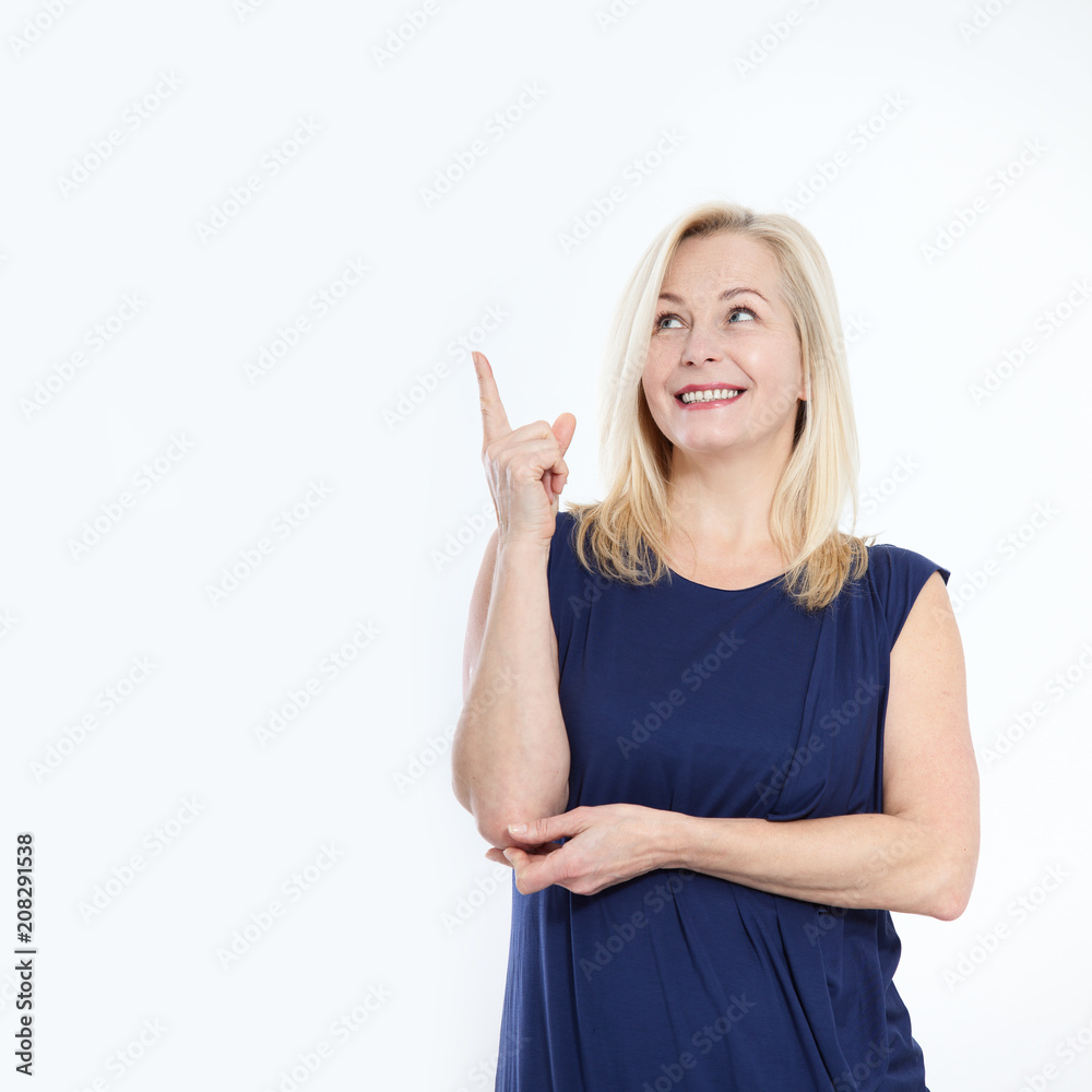 Middle aged beautiful woman in blue dress shows and looks upwards at a ...