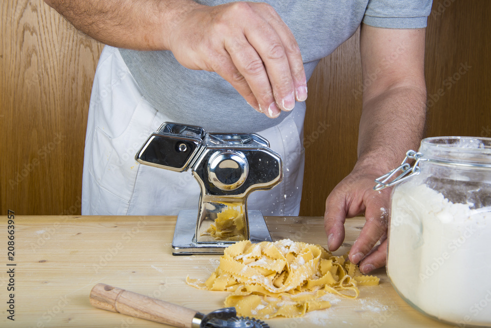 Chef de cocina italiano haciendo pasta fresca con una máquina sus manos ...