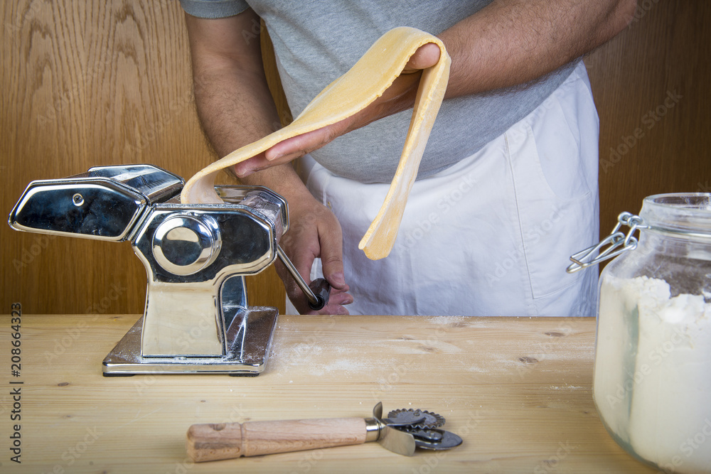 Chef de cocina italiano haciendo pasta fresca con una máquina sus manos ...