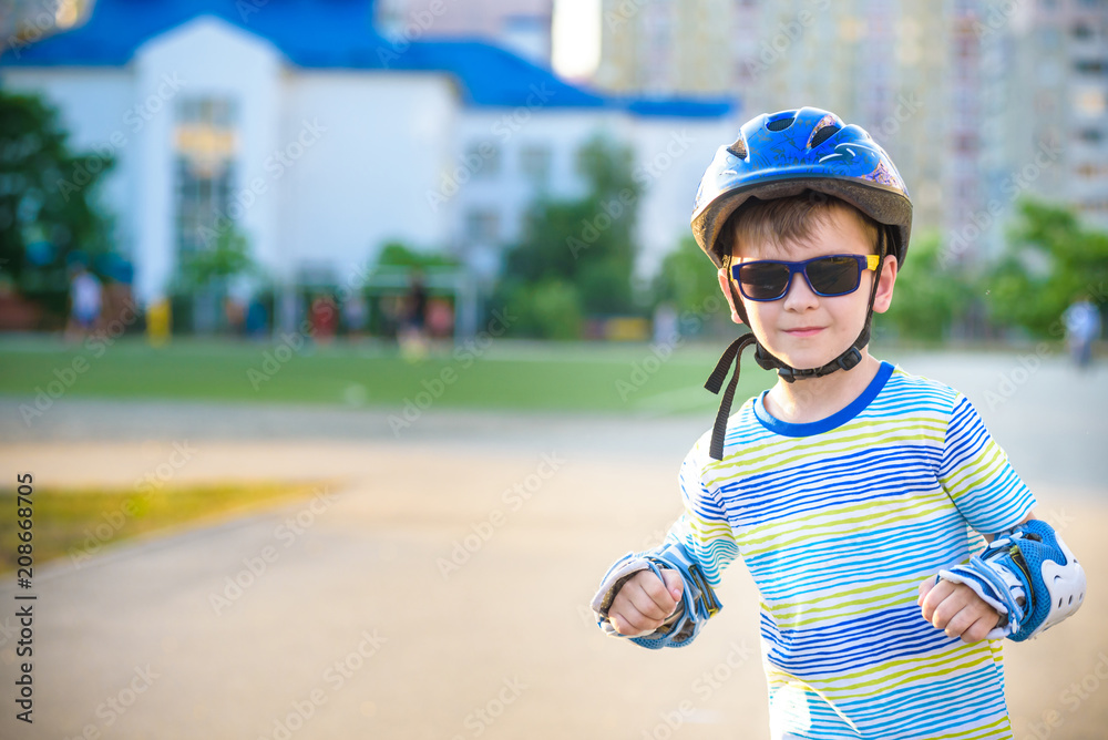 Little boy riding on rollers in the summer in the Park. Happy child in ...
