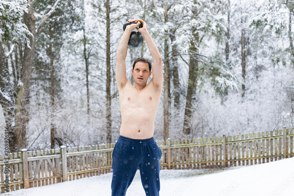 Young fit shirtless man exercising with 45 pound kettlebell and muscles ...