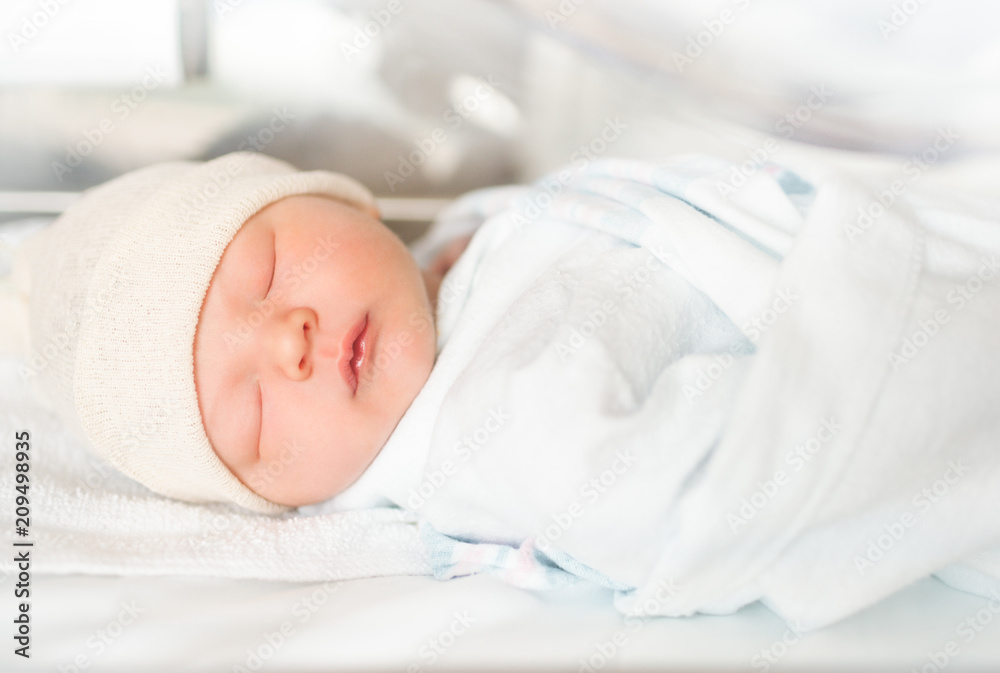 Cute newborn baby boy sleeping in hospital bed. Adobe Stock