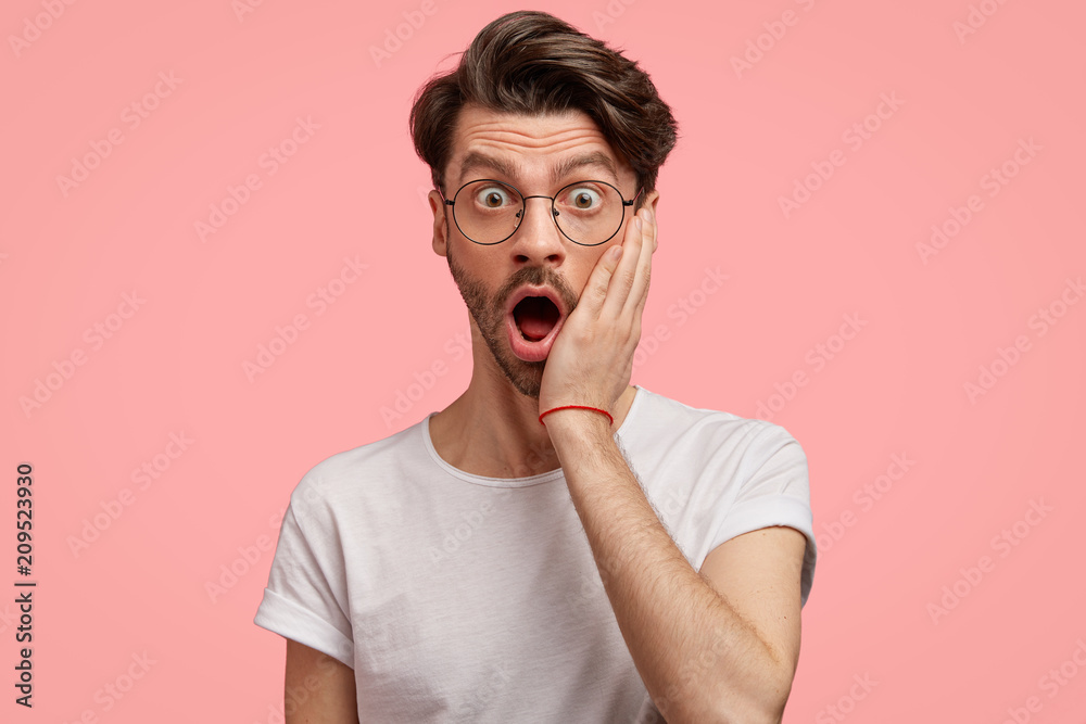 Surprised young European male expresses great confusion, keeps hand on ...