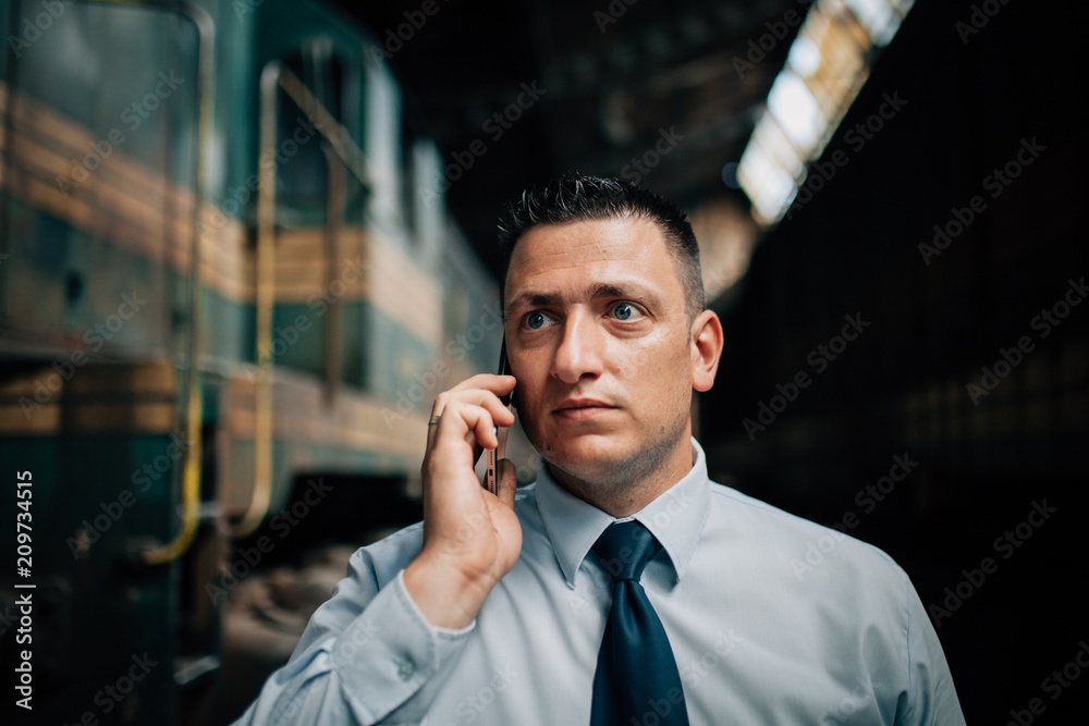 Train driver in front of locomotive call up someone with concerned ...
