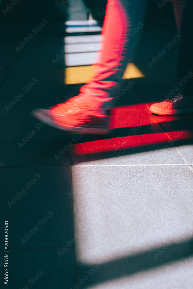 Young man in sneaker walking on the street. Bright light falling down ...