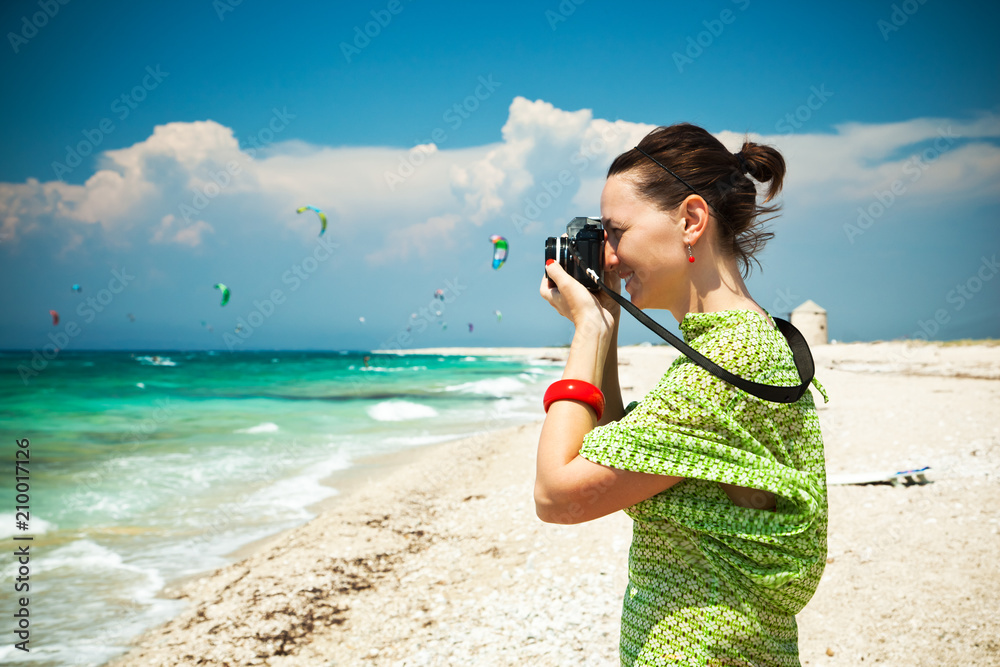 Young woman photographer with analoge camera at the beach shooting kite ...