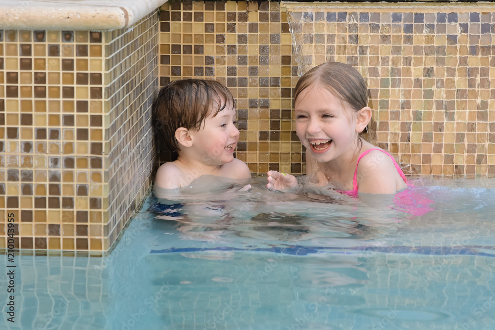adorable brother and sister siblings playing in swimming pool together ...