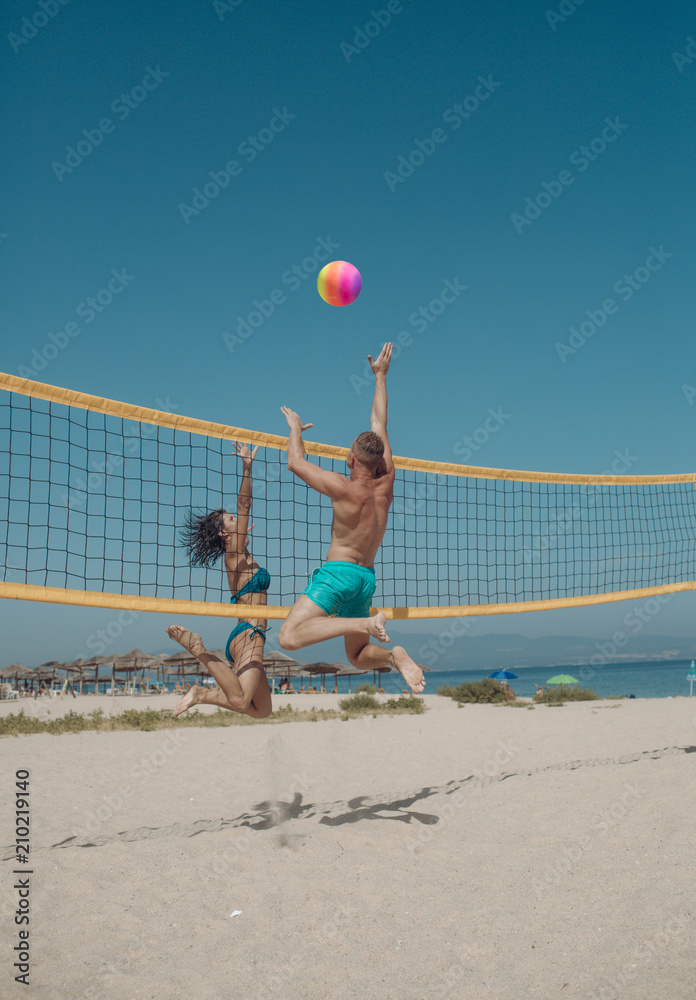 Couple have fun playing volleyball. Young sporty active couple beat off ...