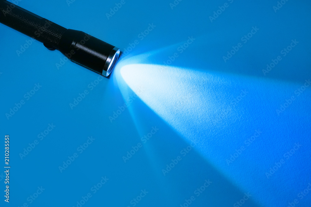 flashlight and a ray of light in the dark on a blue background. A ...