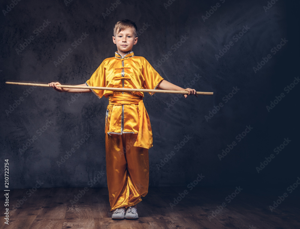 Cute boy dressed in the traditional costume of a Tibetan monk shows the ...