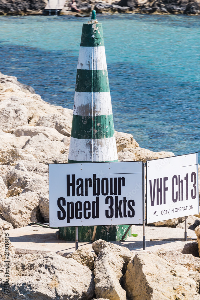 Sign at the entrance to a harbour showing a 3kts speed limit, and the ...