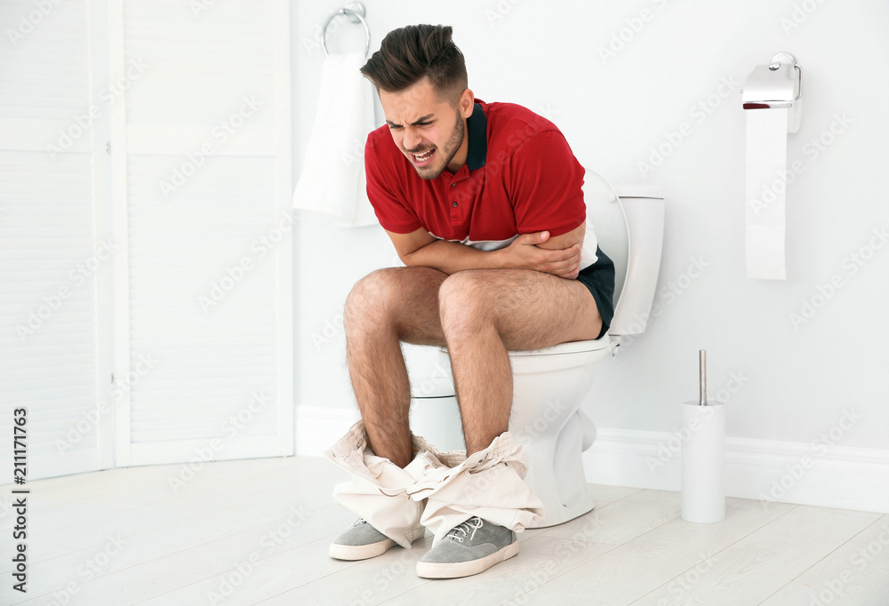 Young man suffering from diarrhea on toilet bowl at home Stock Photo ...