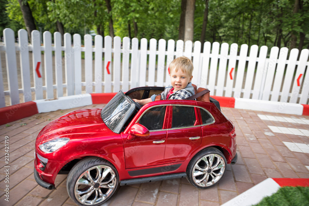 Little smiling boy is driving a car on kid's go-karting. Three year-old ...