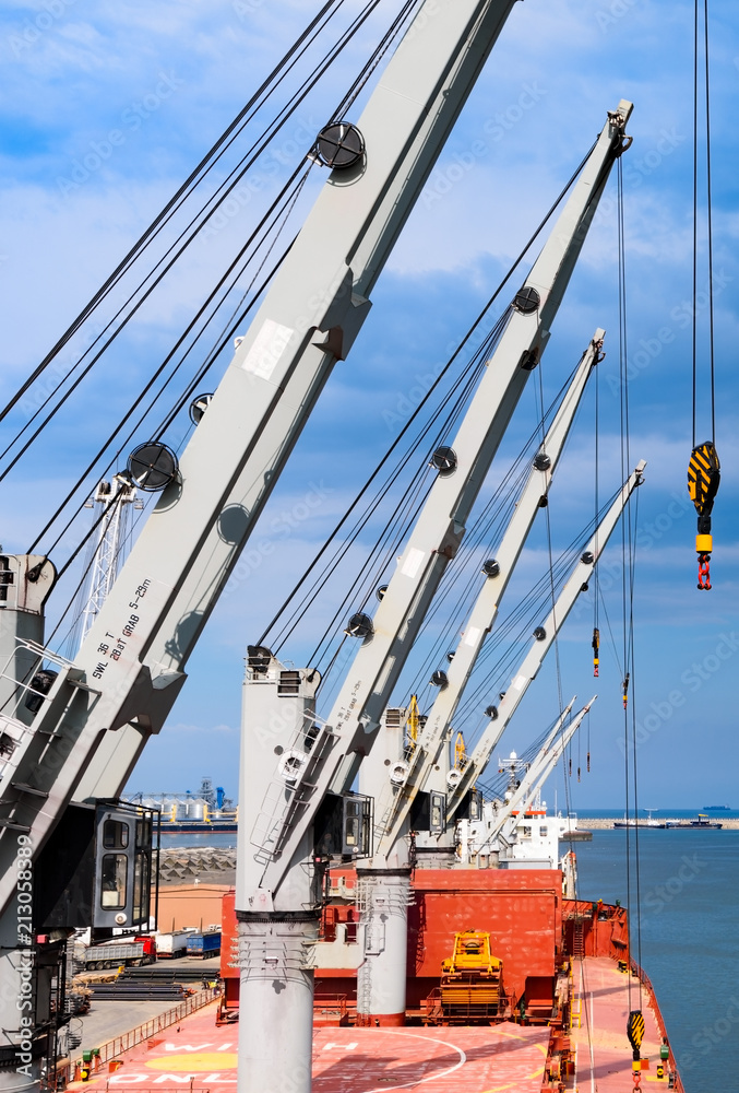 Ship’s cargo gear ready for cargo operations in port with deep blue sky ...