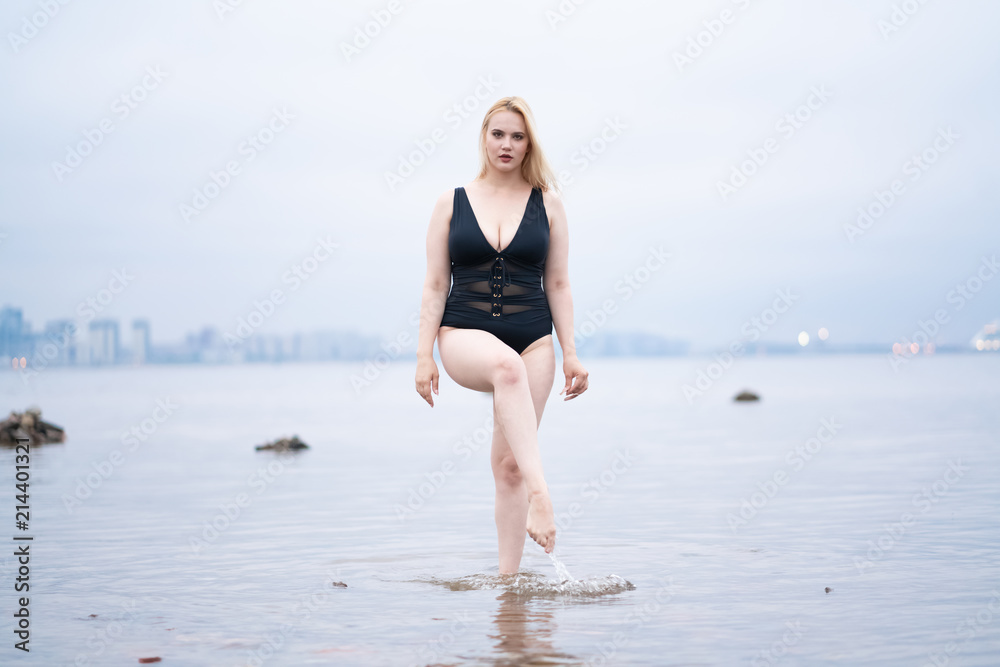 beautiful European plus size girl posing in black swimsuit on the beach ...