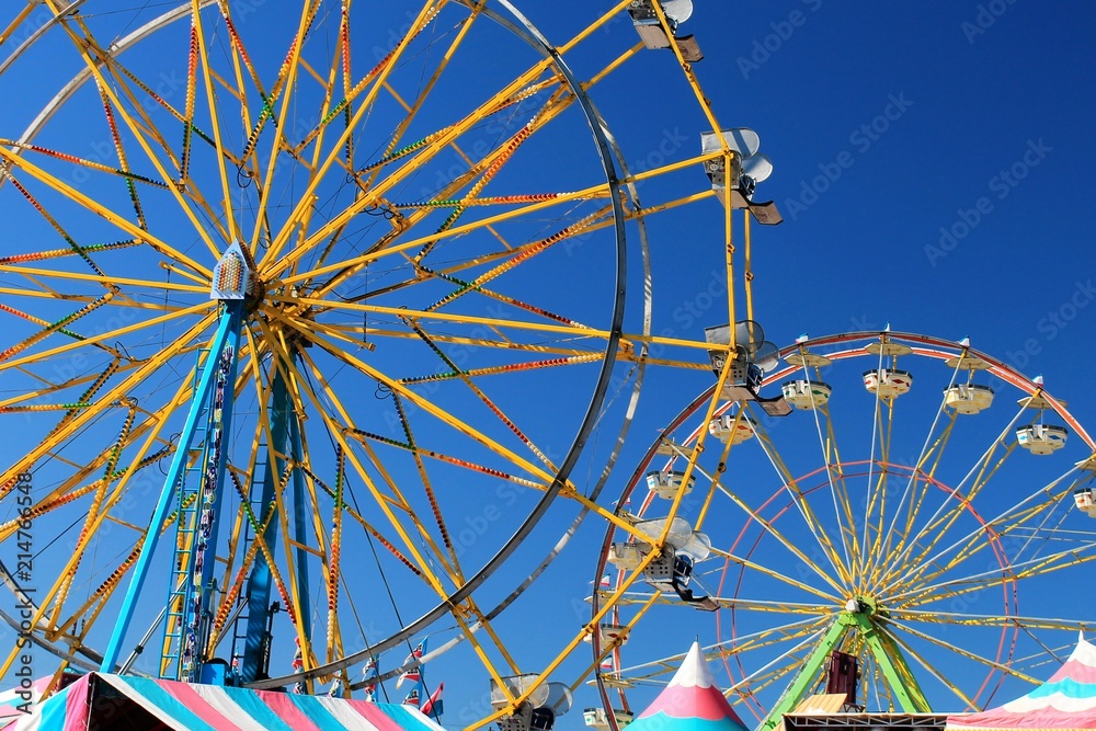 Two colorful ferris wheels with blue sky background Stock Photo | Adobe ...