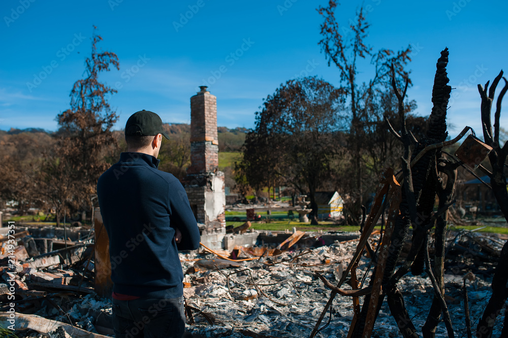 Man owner checking burned and ruined house and yard after fire ...