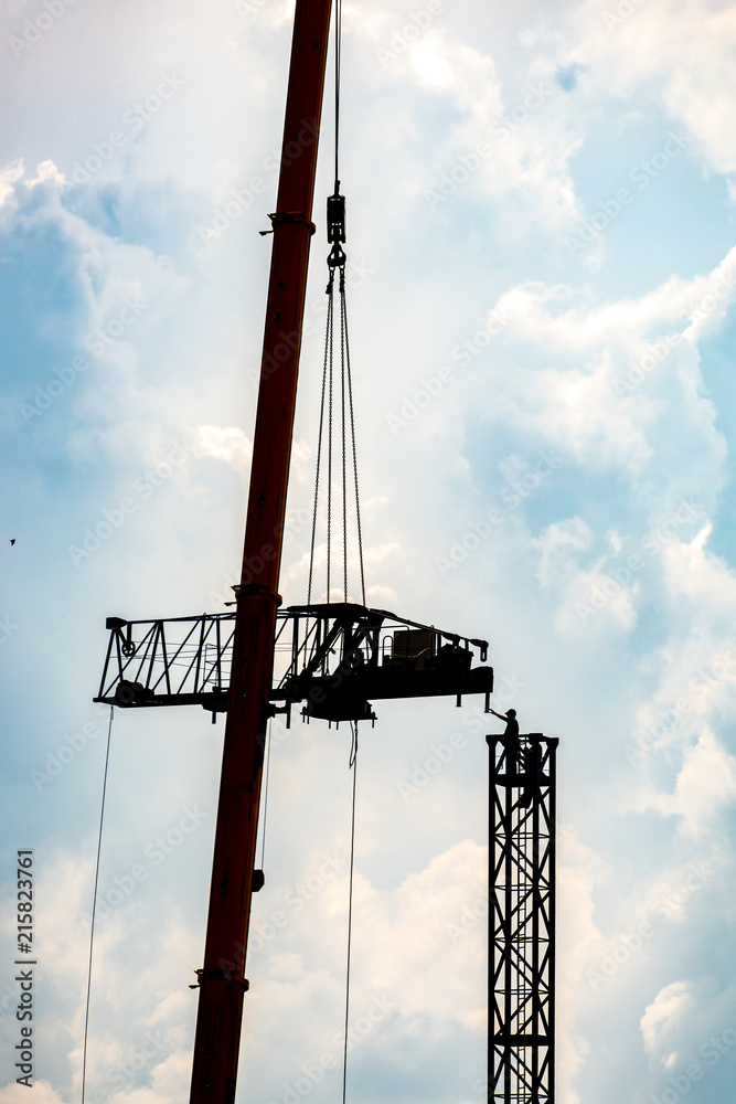 Silhouette of worker catching the jib of a blue tower crane in the ...