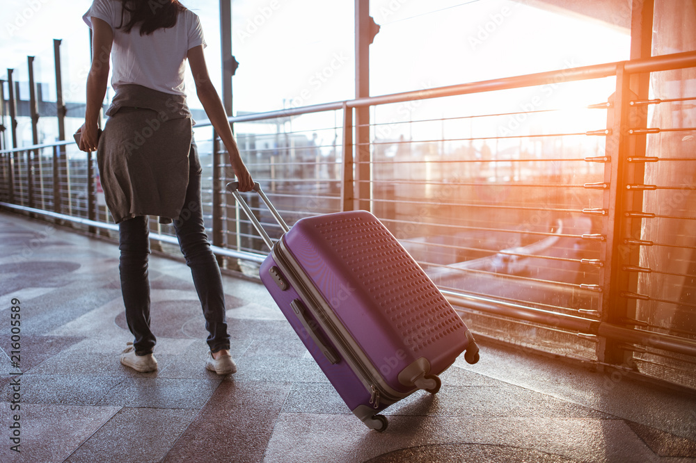 Young woman pulling suitcase in modern airport terminal. Travelling guy ...