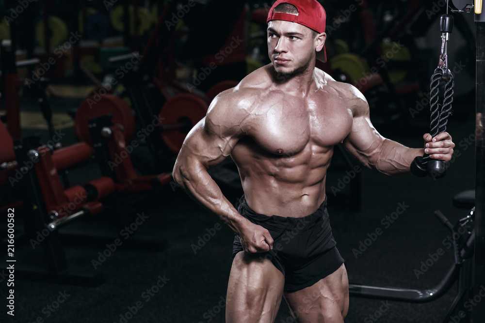Muscular athletic bodybuilder fitness model posing and exercises in gym ...