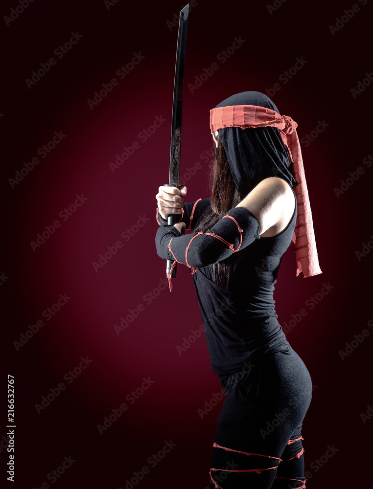 Beautiful samurai woman warrior with a sword in studio on red dark ...