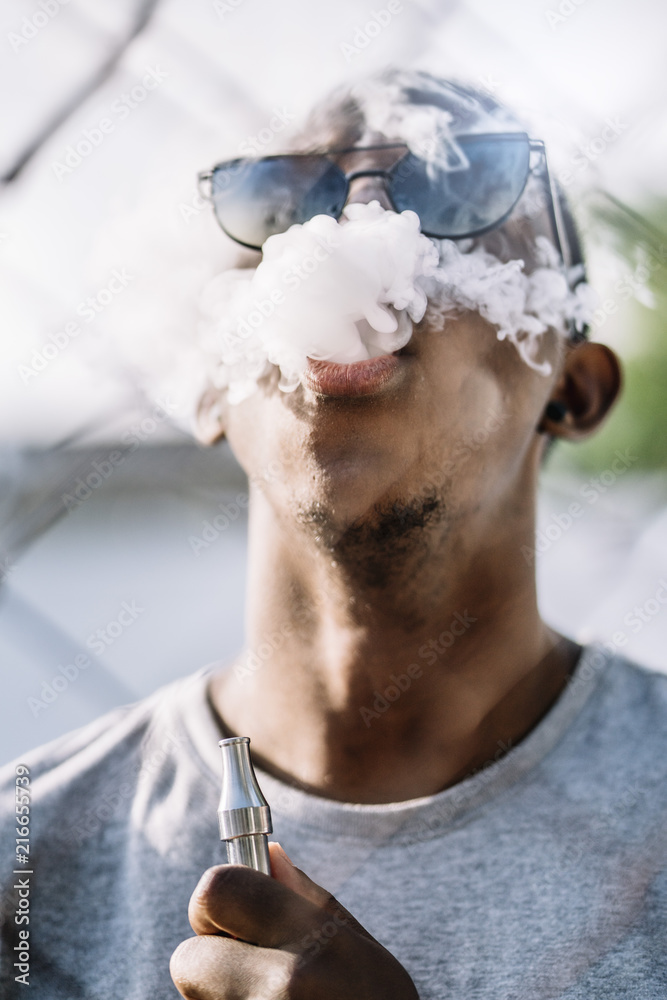 African man smoking white smoke hookah. Stock Photo | Adobe Stock