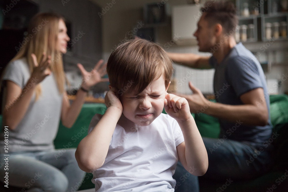 Frustrated kid son puts fingers in ears not listening to noisy parents ...