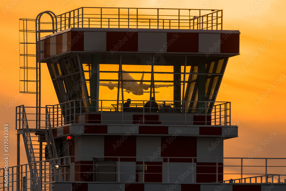 Stockfoto Airplane flying behind airport control tower during sunset ...