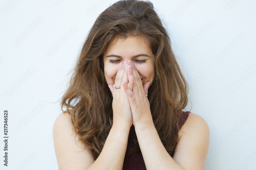 Embarrassed girl laughing and covering mouth with hands. Pretty young ...