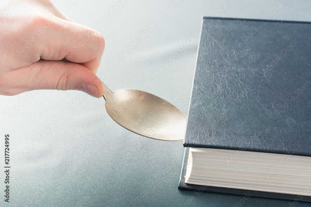 Silver spoon in his hand opens the cover of a thick black book Stock ...
