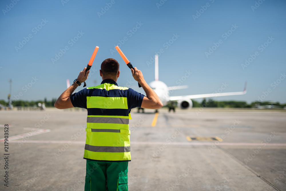 Directing the jet. Back view of aviation marshaller at airport ...