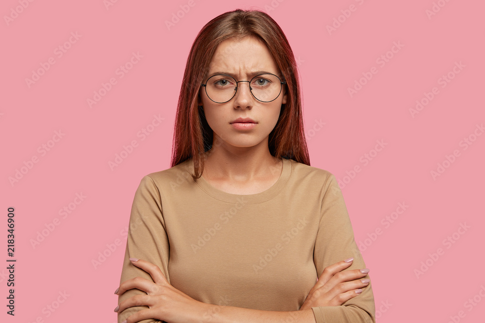 Displeased sullen female has discontent expression, keeps hands crossed ...